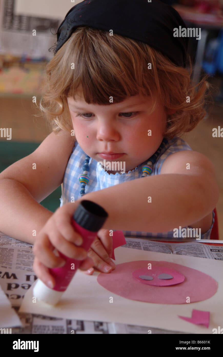 Little girl glueing shapes on a picture at nursery Stock Photo - Alamy