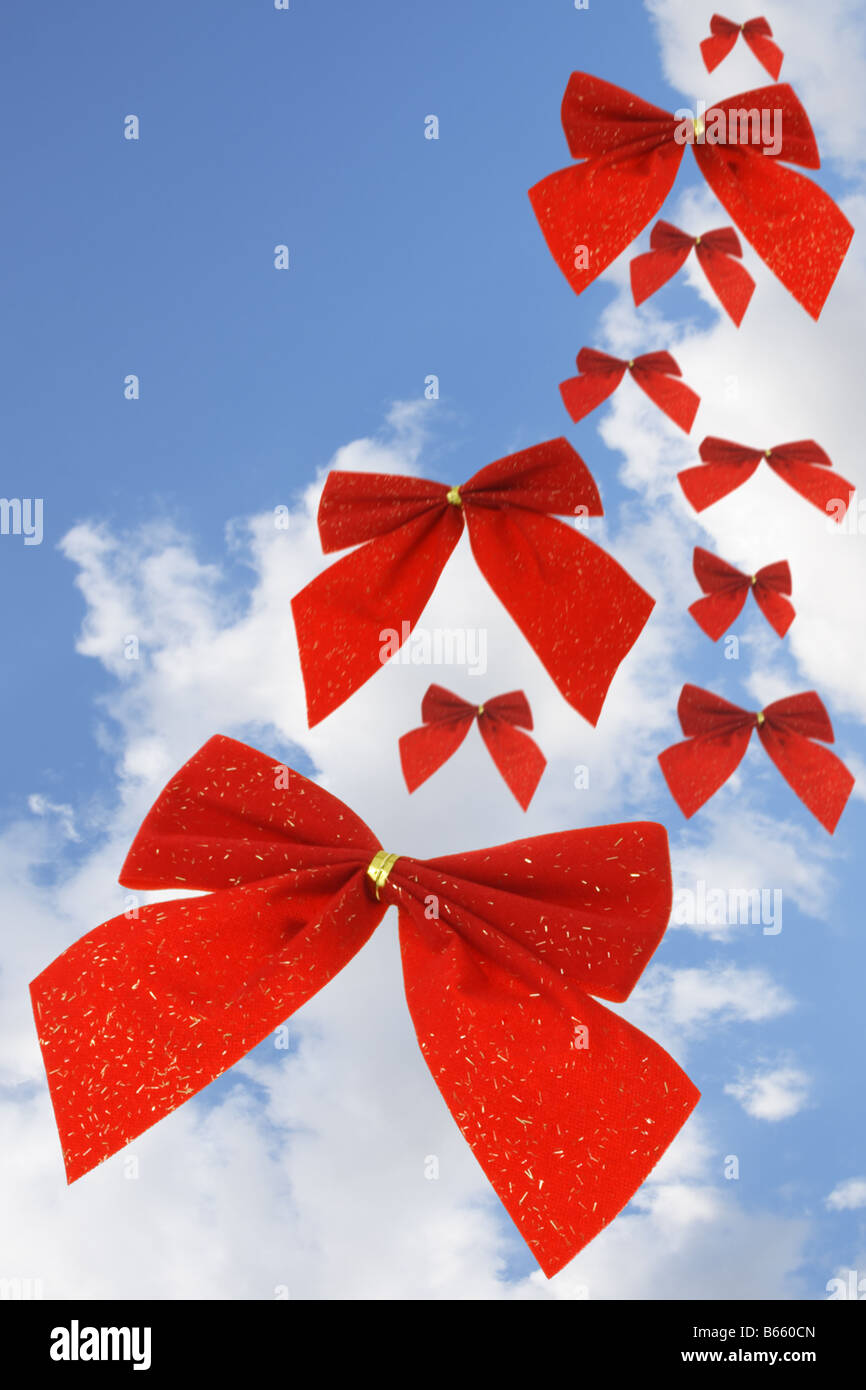 Red bow ribbons falling against a cloudy sky background Stock Photo - Alamy