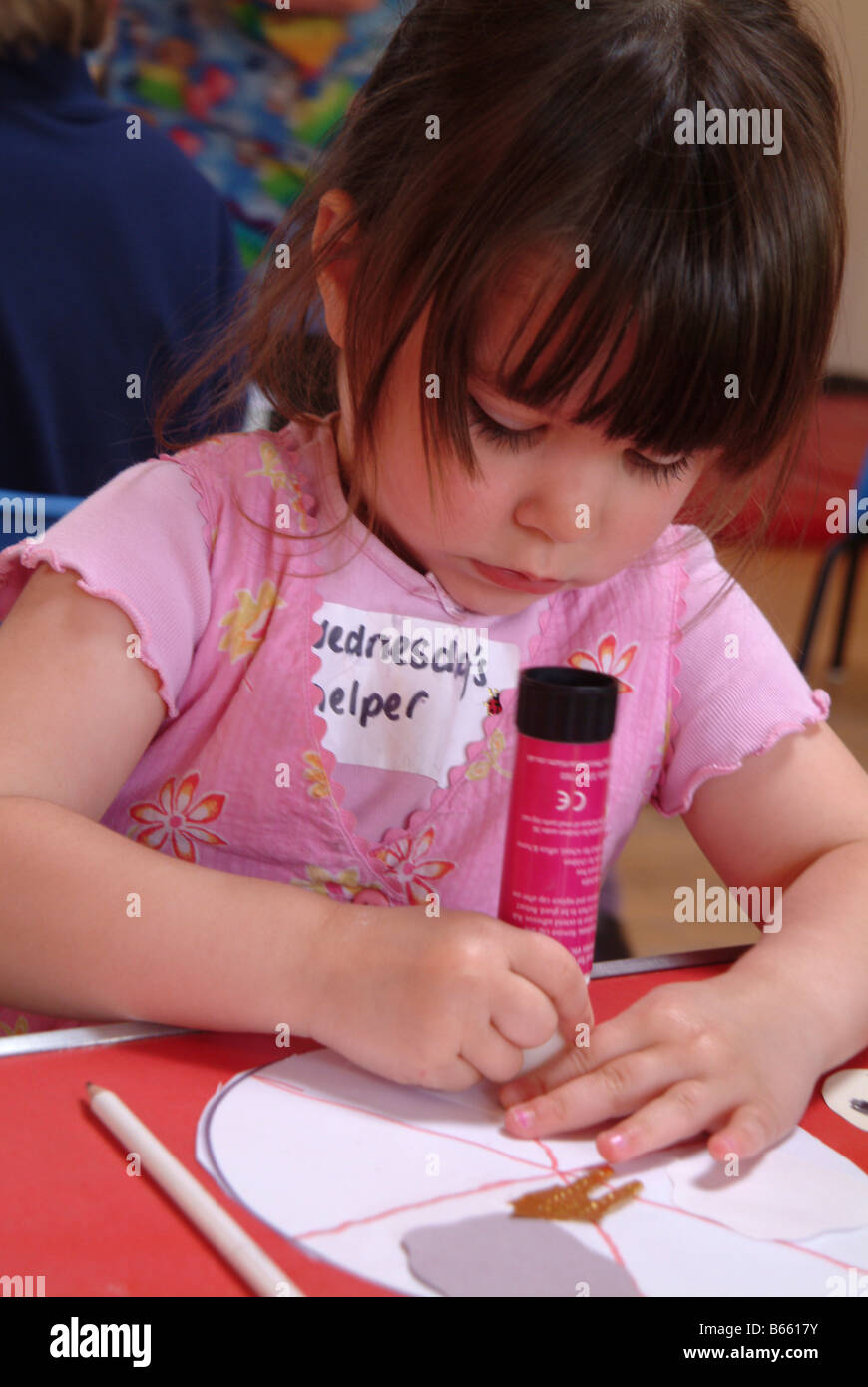 Little girl glueing a picture at nursery Stock Photo - Alamy
