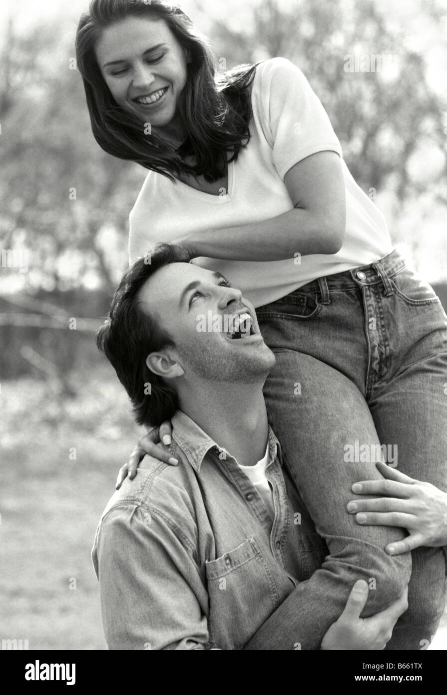 Young man carrying woman, smiling Stock Photo - Alamy