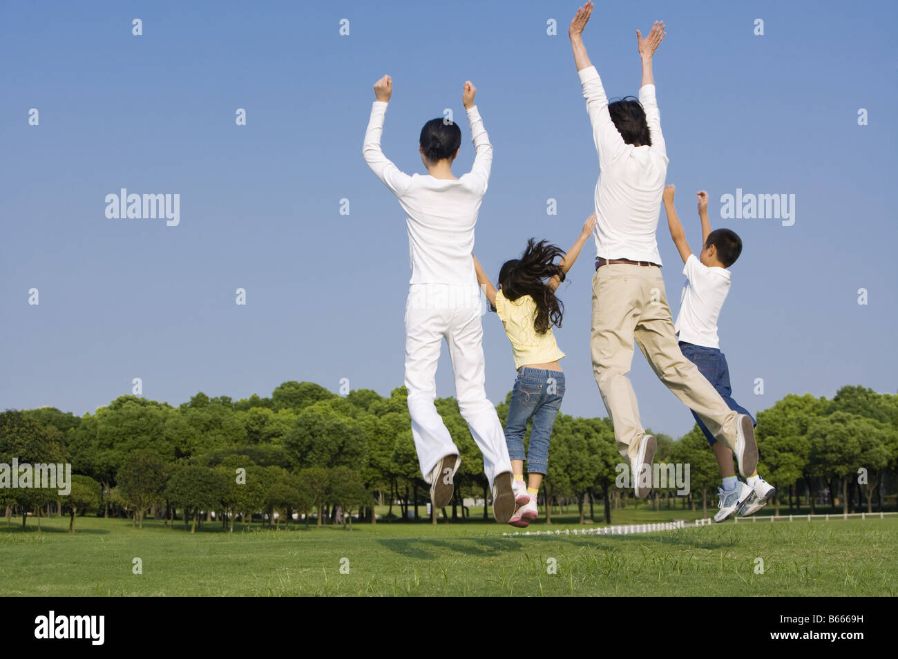 Family with two children jumping on the lawn Stock Photo - Alamy