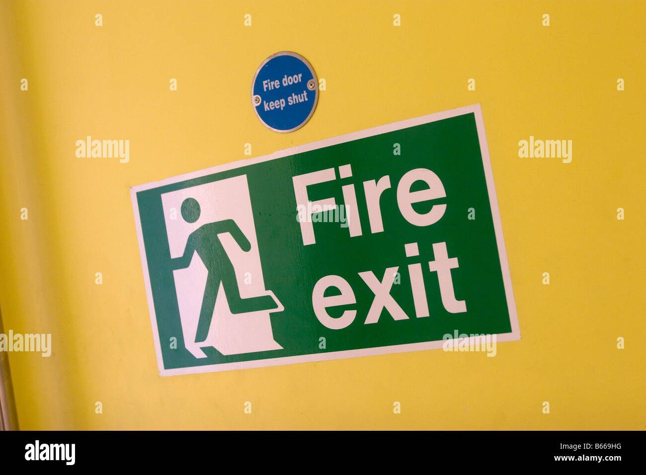 Fire Exit Sign green and white on yellow wall Stock Photo - Alamy