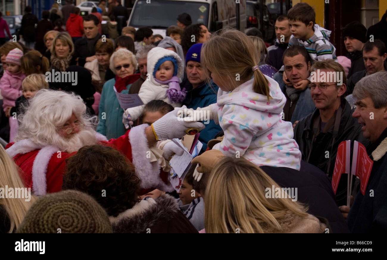 Father Christmas reaches out to a small child giving her Christmas list ...