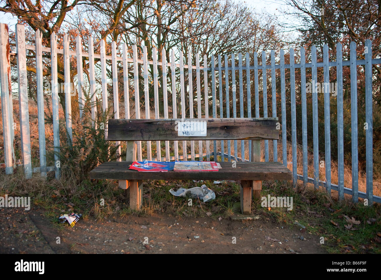 park bench backed by security fence Stock Photo - Alamy