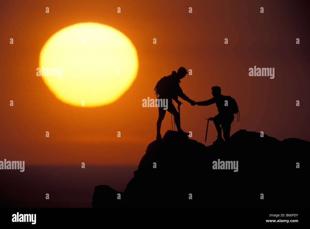 Two climbers reach the summit at sunrise Stock Photo - Alamy