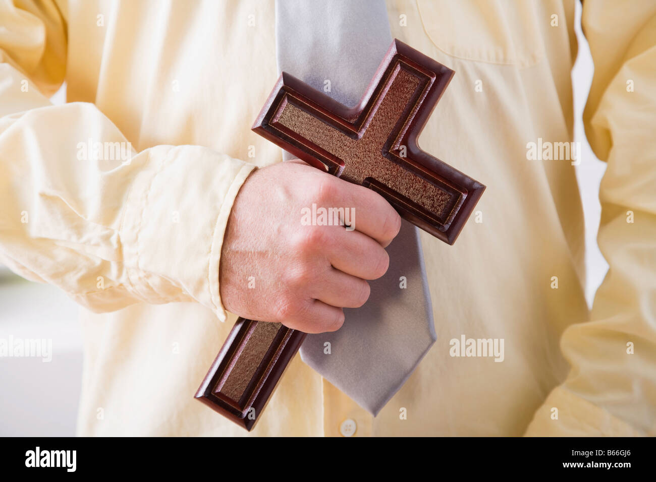 Mid section of man holding Christian cross Stock Photo - Alamy