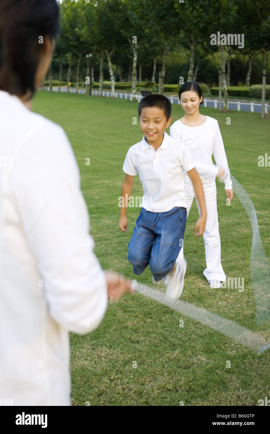Young family with child jumping rope on the lawn Stock Photo - Alamy