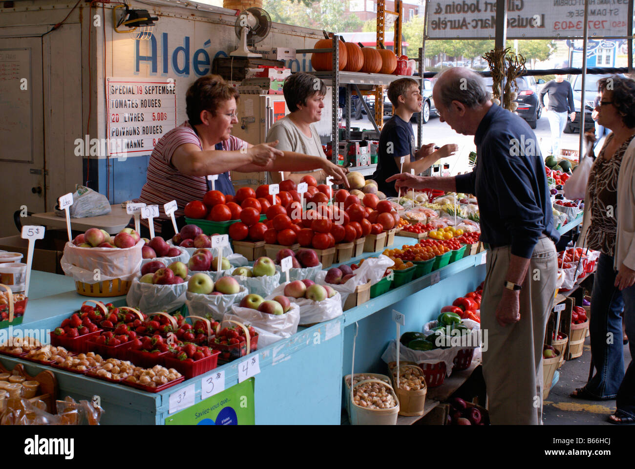 People shopping at a fruit and vegetable stand in the Atwater Market ...