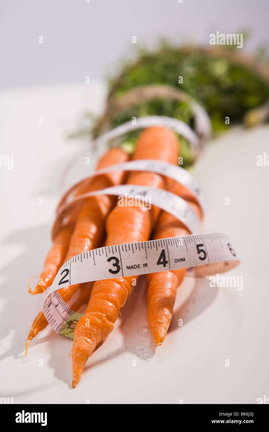Tape measure wrapped around bunch of carrots Stock Photo - Alamy