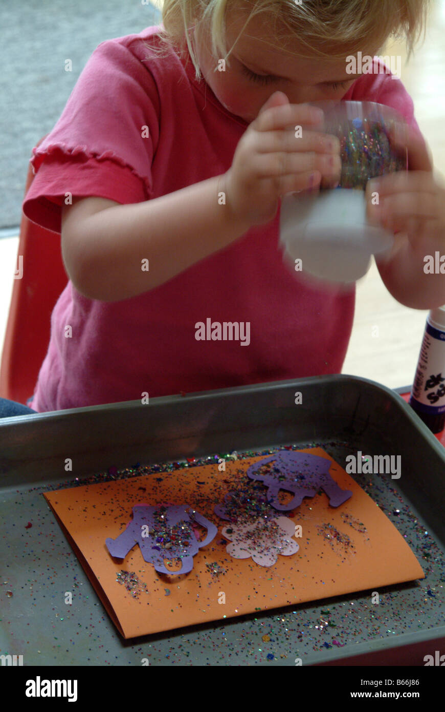 Girl sprinkling glitter on a picture at nursery Stock Photo - Alamy