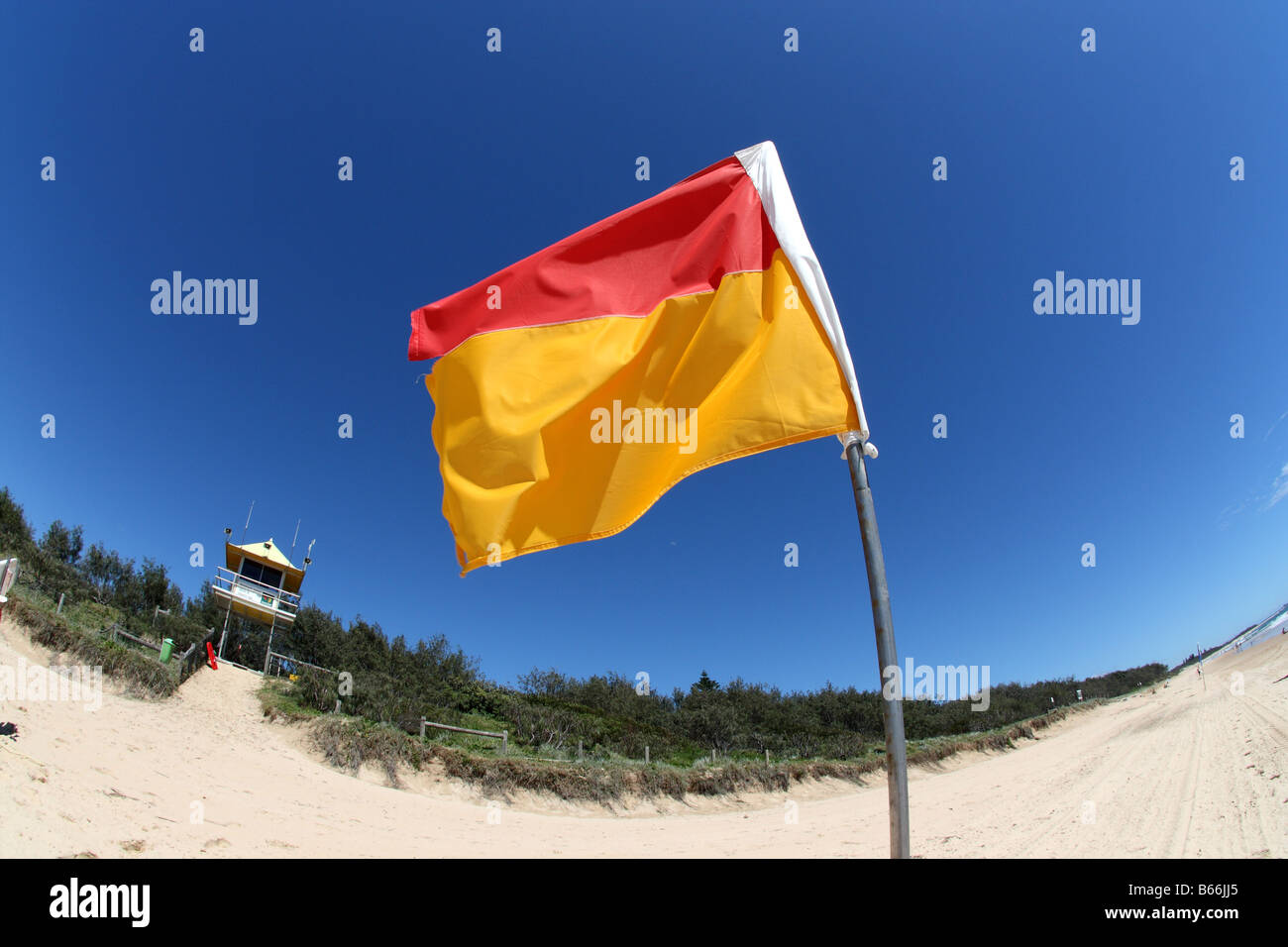 FISHEYE PHOTO OF A RED AND YELLOW BEACH FLAG AND RESCUE TOWER ON A ...