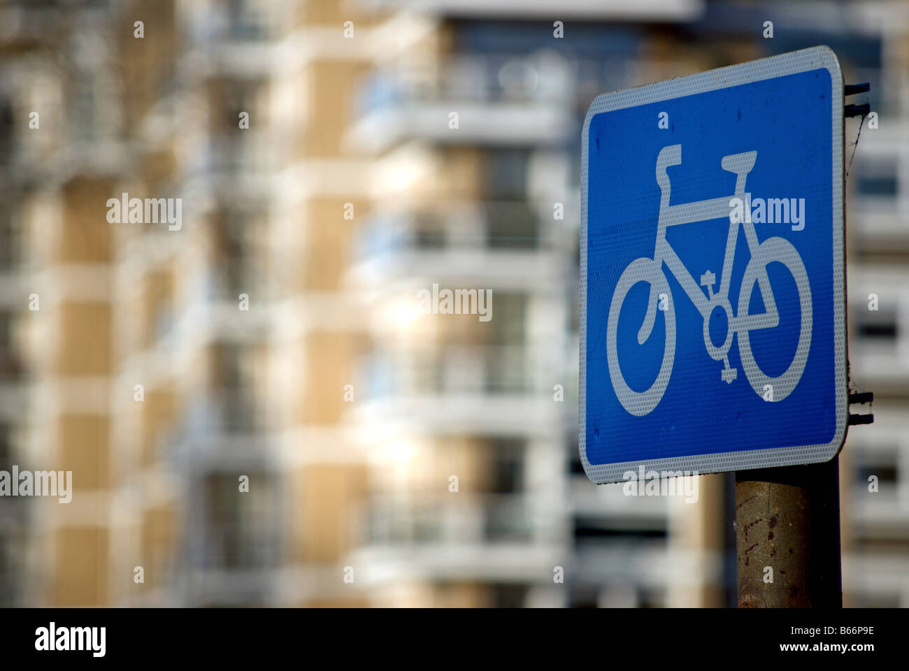 blue and white cycle path sign againt a background of highrise ...