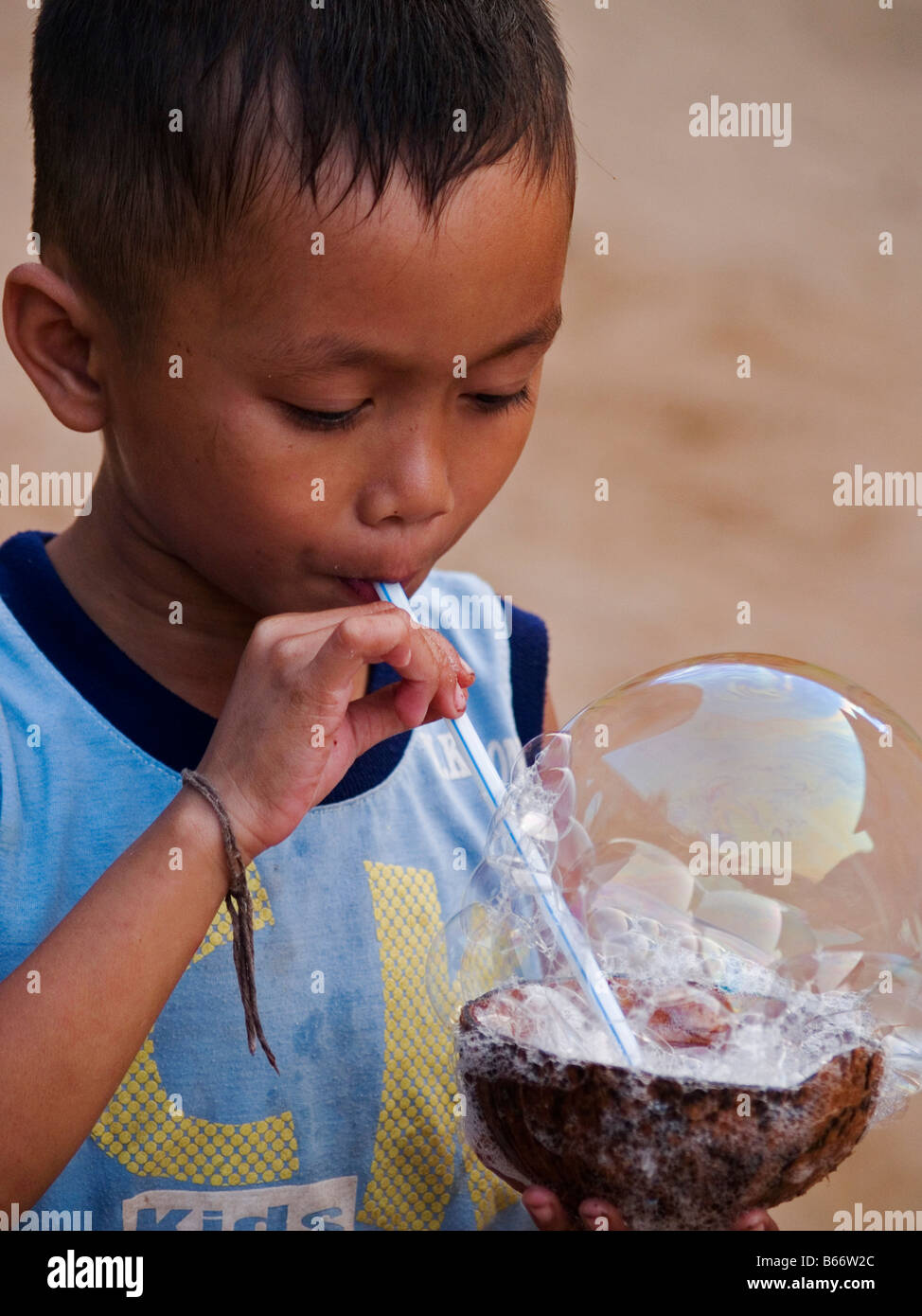 boy blowing bubbles from a coconut shell in northern Laos Stock Photo ...