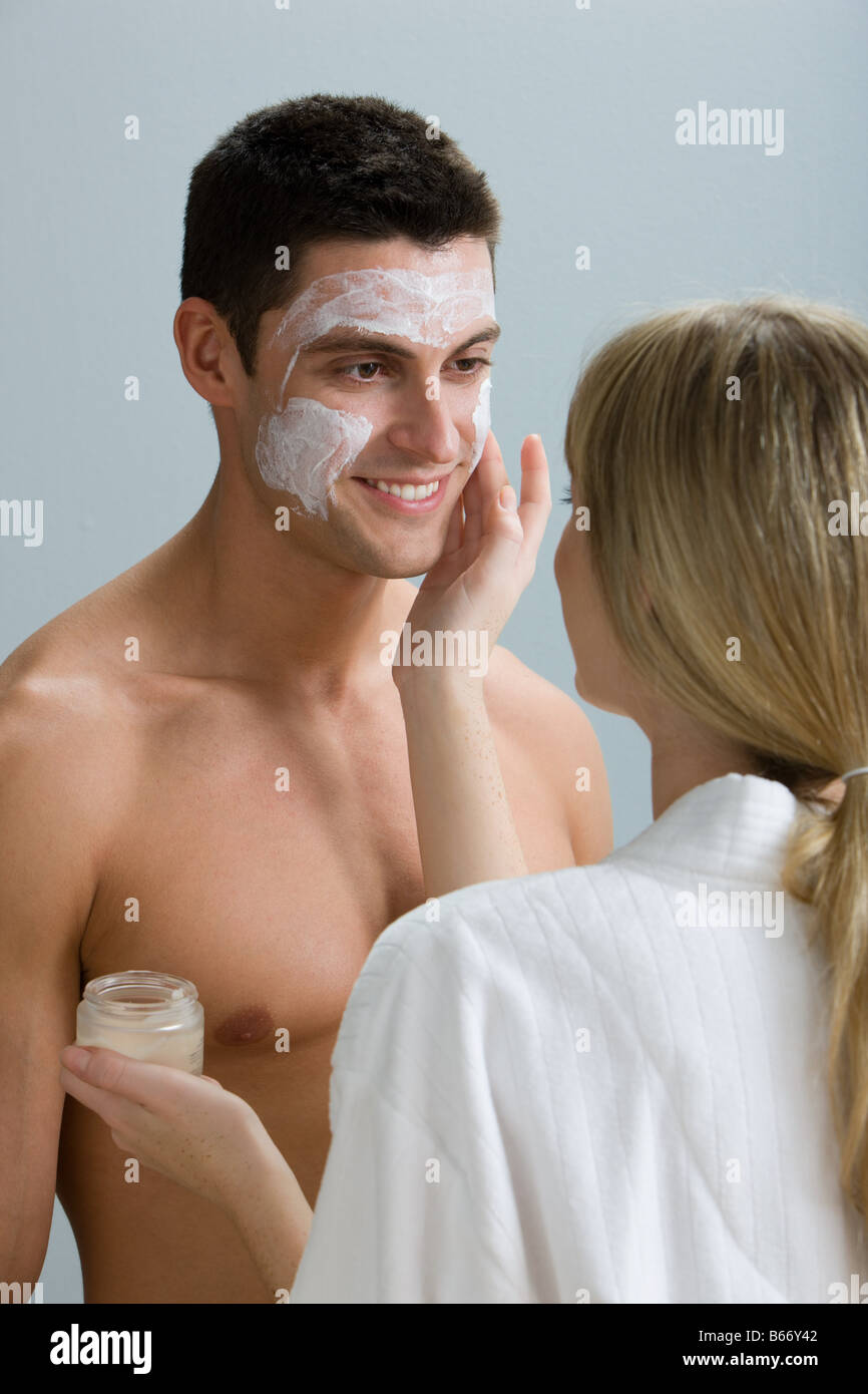 A woman applying face mask to a mans face Stock Photo - Alamy