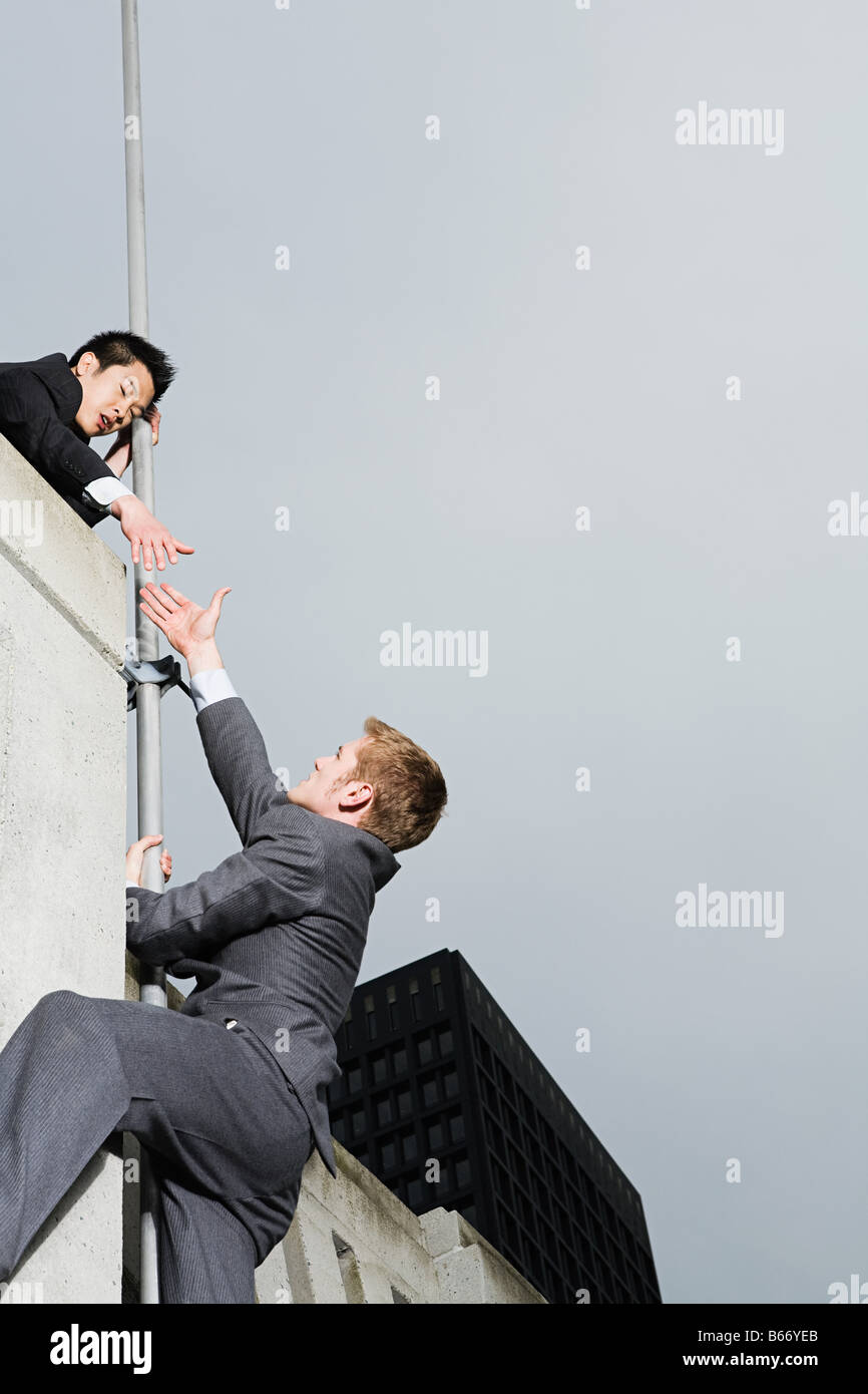 Businessman reaching colleague over wall Stock Photo - Alamy