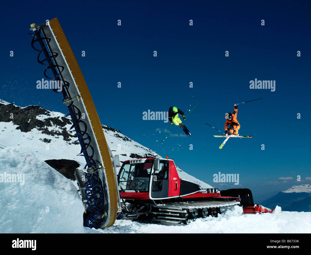 Skiers jumping piste machine Stock Photo - Alamy