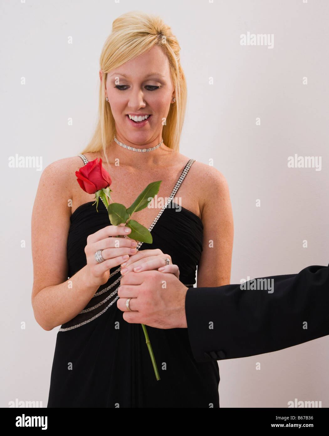 Smiling woman receiving red rose from man Stock Photo - Alamy