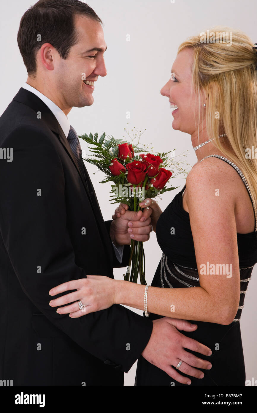 Smiling woman receiving red roses from man Stock Photo - Alamy