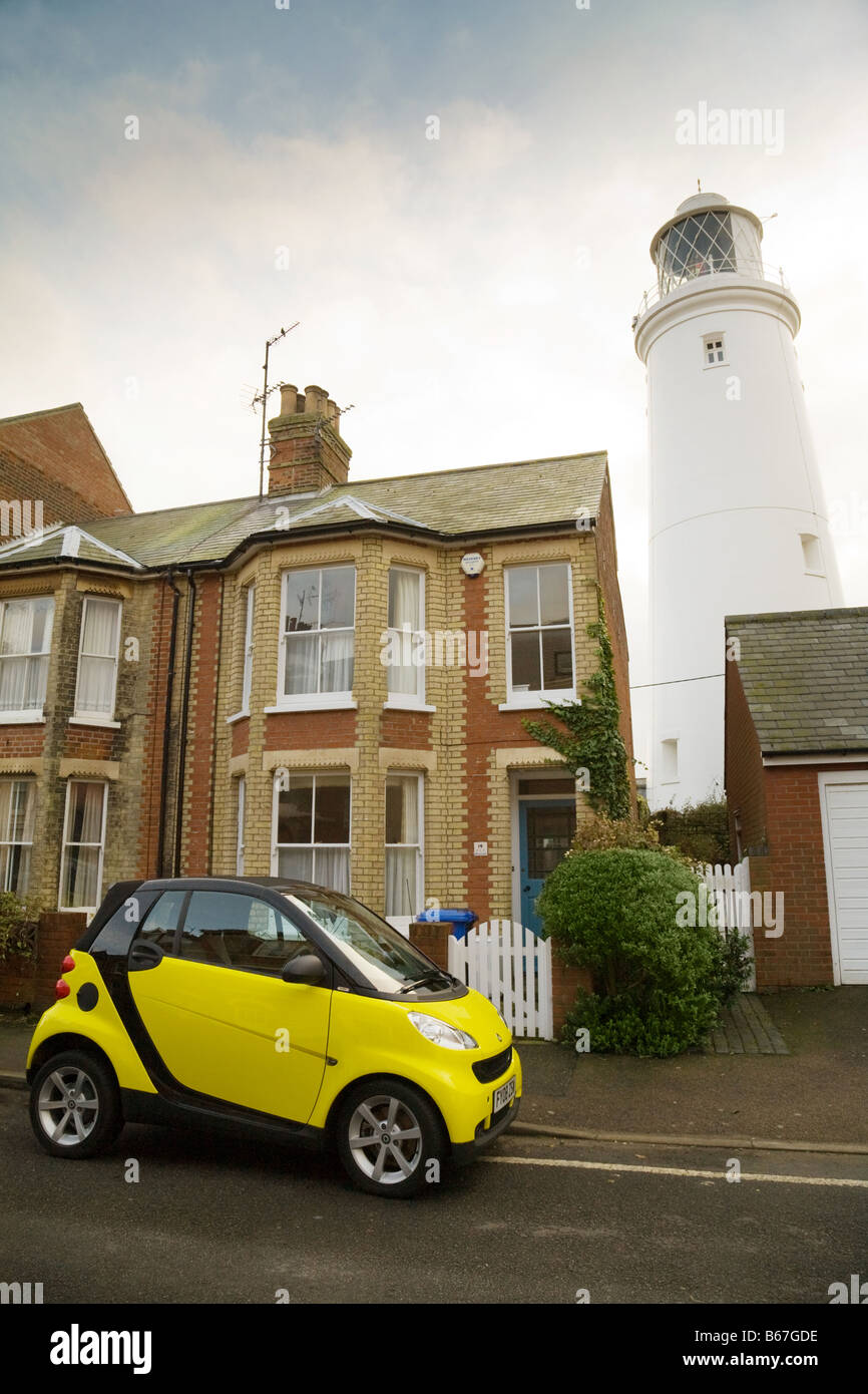 A Yellow smart car with the lighthouse, Southwold, in the background ...
