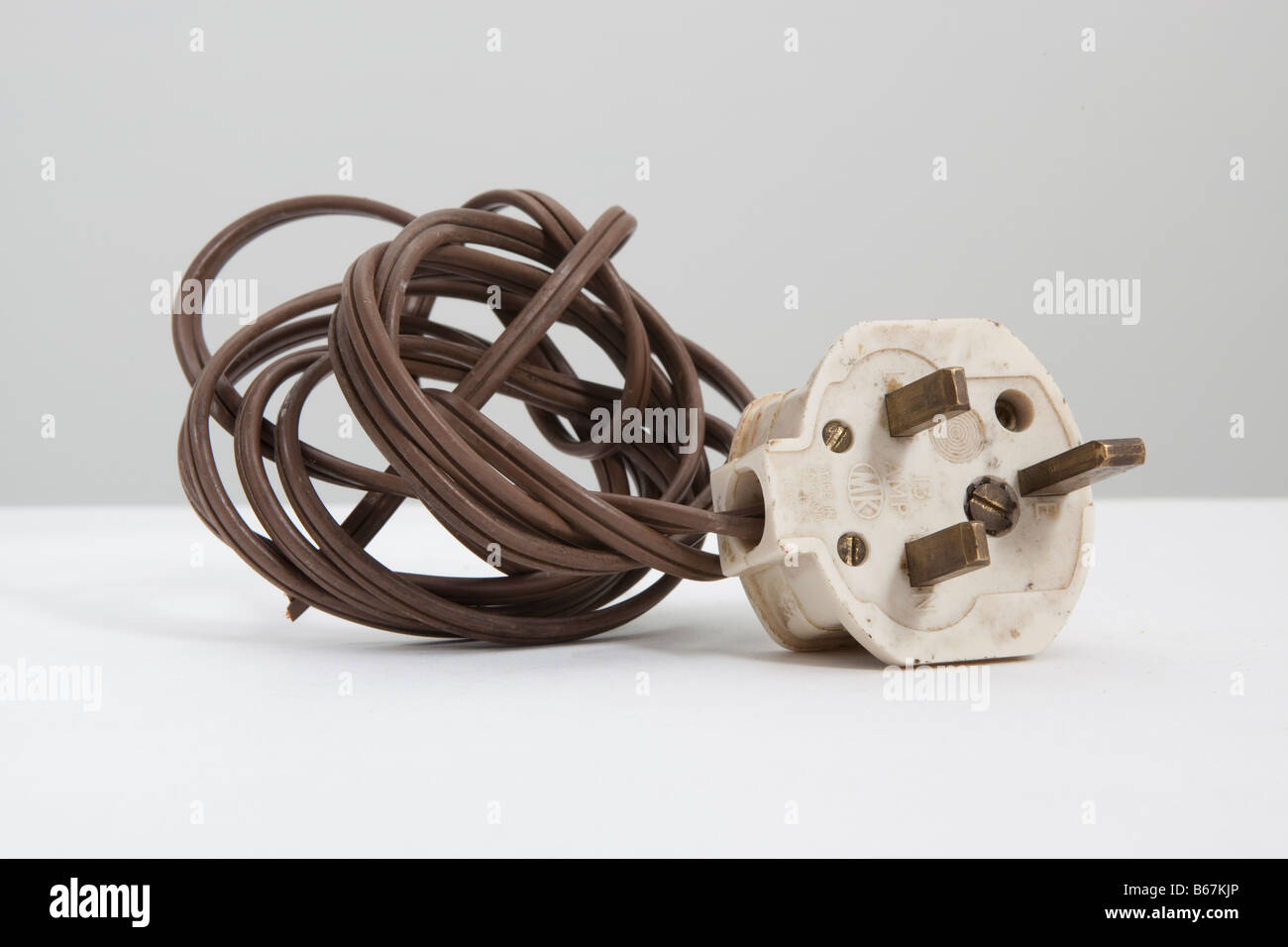old white , UK standard 13 amp electrical plug and coil of brown flex ...