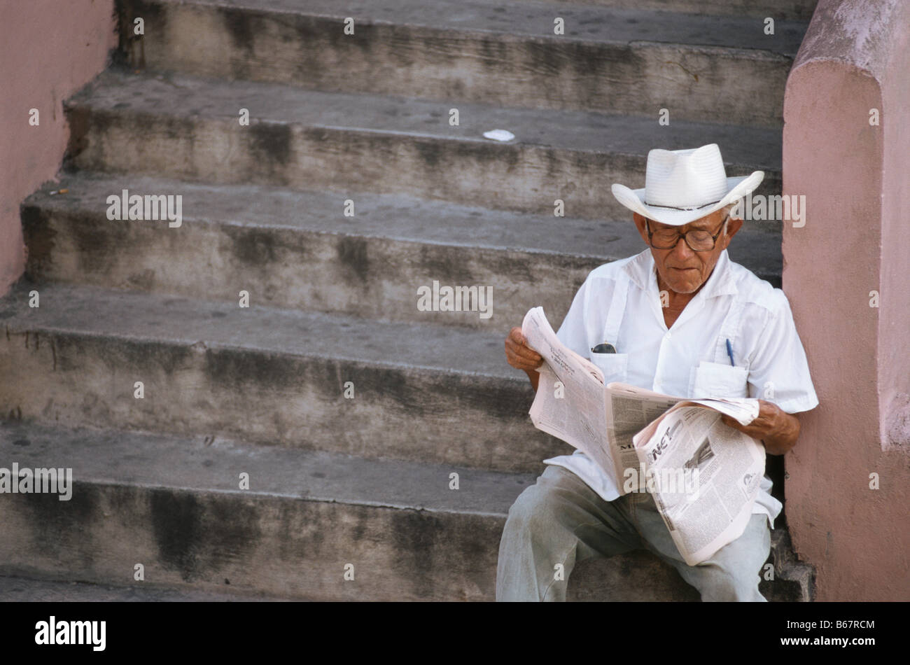 Mexican man sitting on the steps and reading a newspaper, Market ...