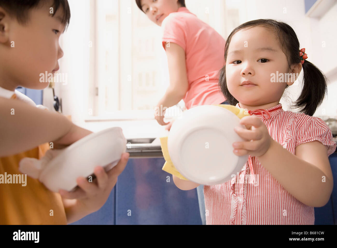 Close-up of a girl drying plates with her brother Stock Photo - Alamy