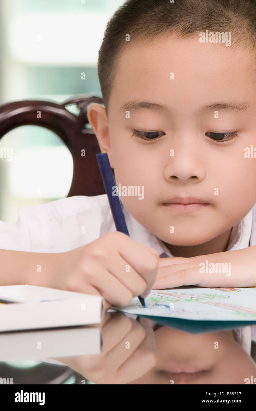 Close-up of a boy looking down and writing on a sheet of paper Stock ...