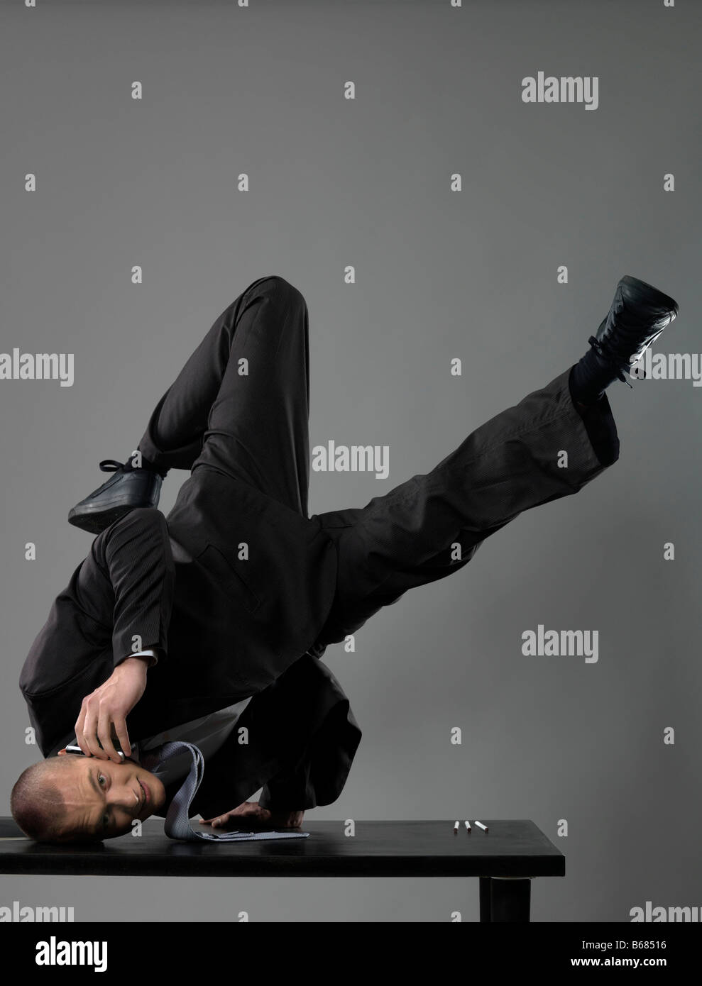 Business man balancing on table Stock Photo - Alamy