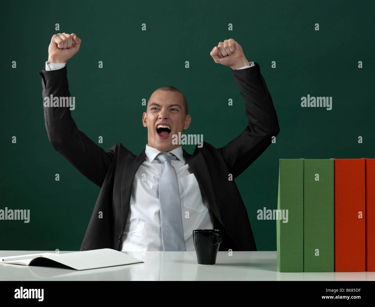 Business man cheering by office table Stock Photo - Alamy