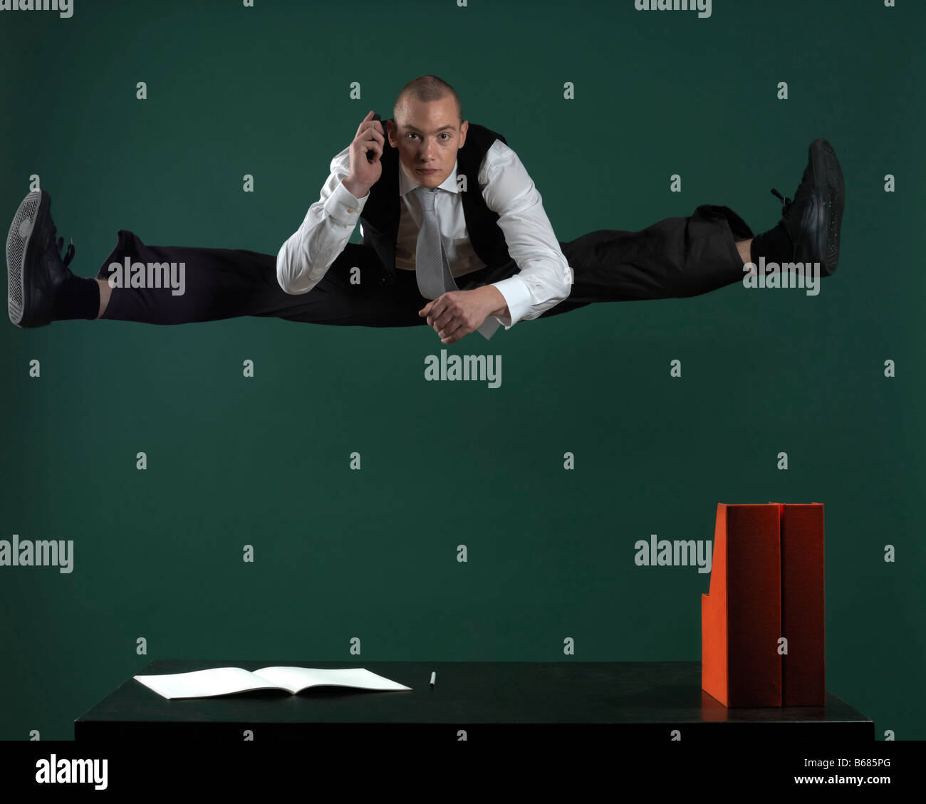 Business man jumping over desk Stock Photo - Alamy