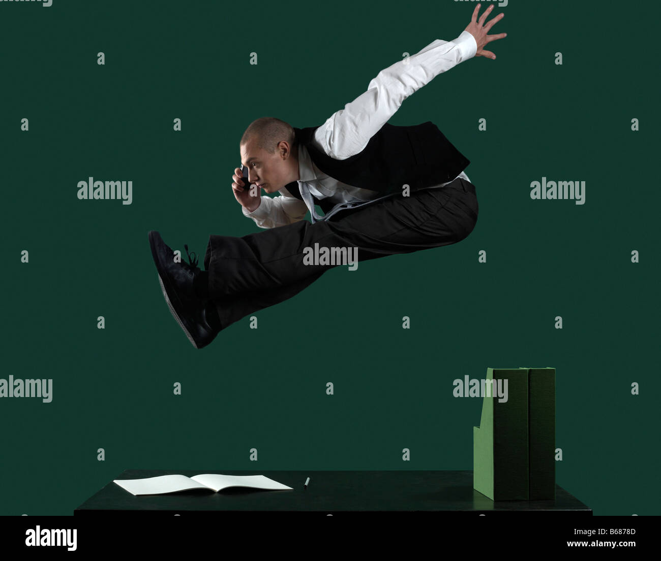 Business man jumping over desk Stock Photo - Alamy
