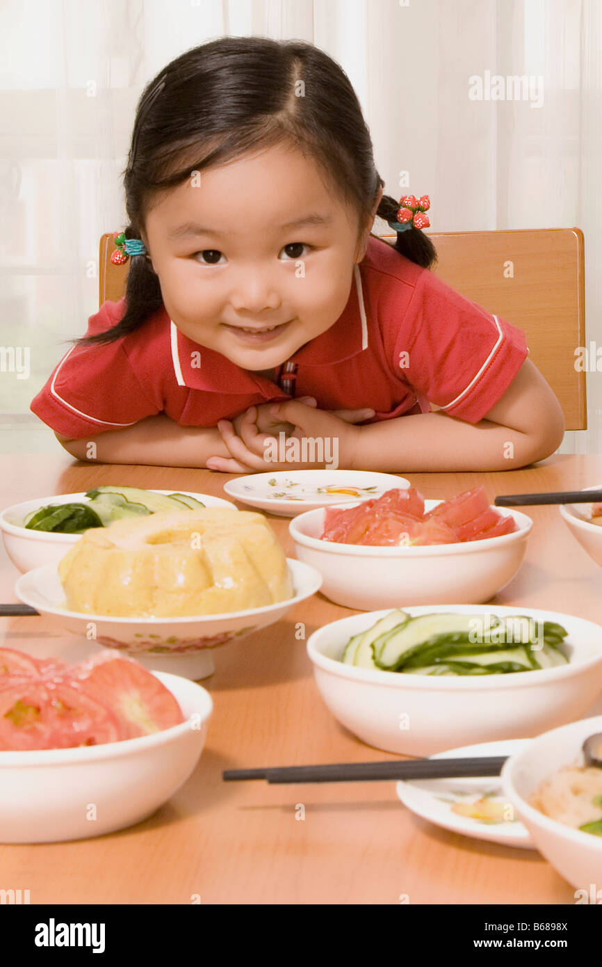 Portrait of a girl sitting at a dining table and smiling Stock Photo ...