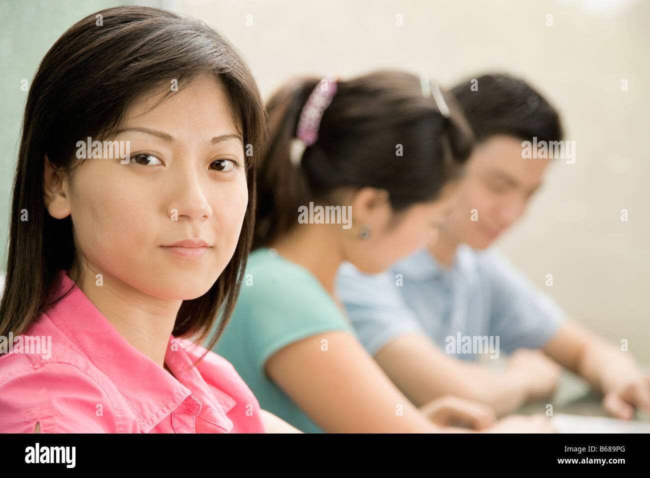 Portrait of a female office worker with two other office workers ...