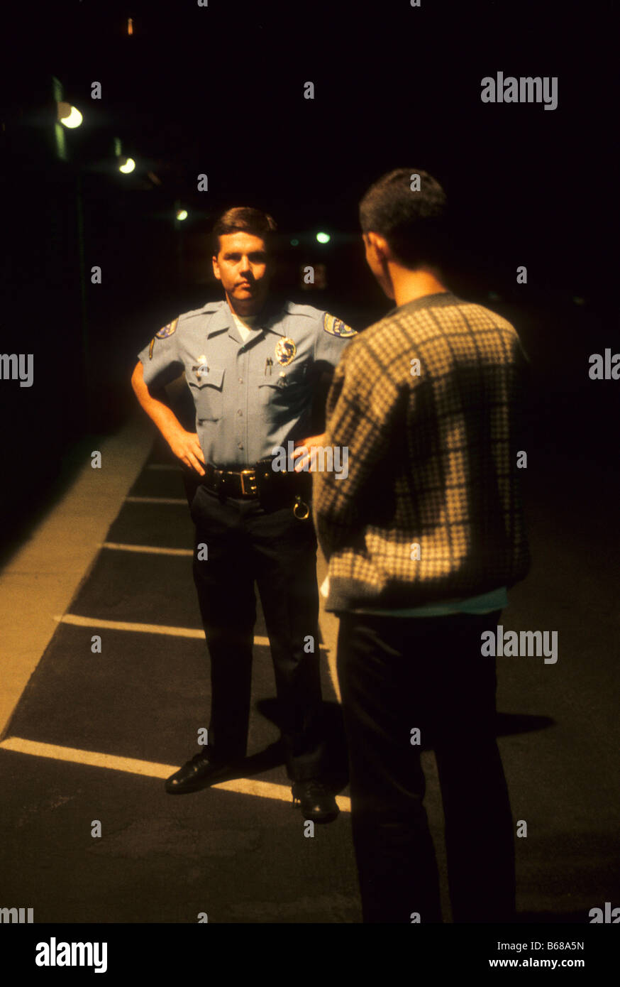 Police officer talks with young man on street at night Stock Photo - Alamy