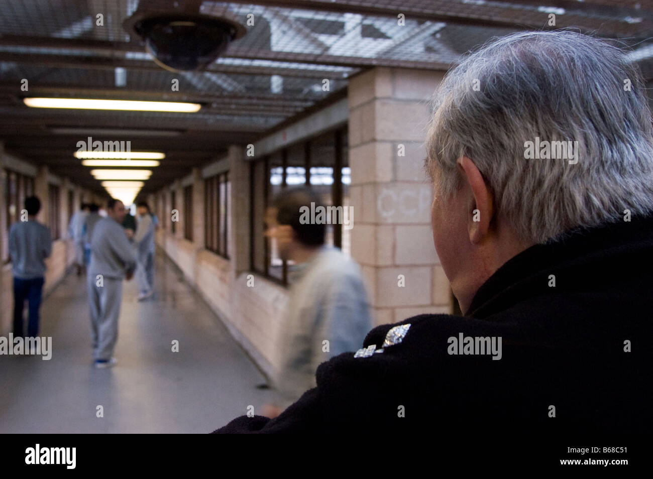Back view of Prison officer watching out of focus prisoners Stock Photo ...