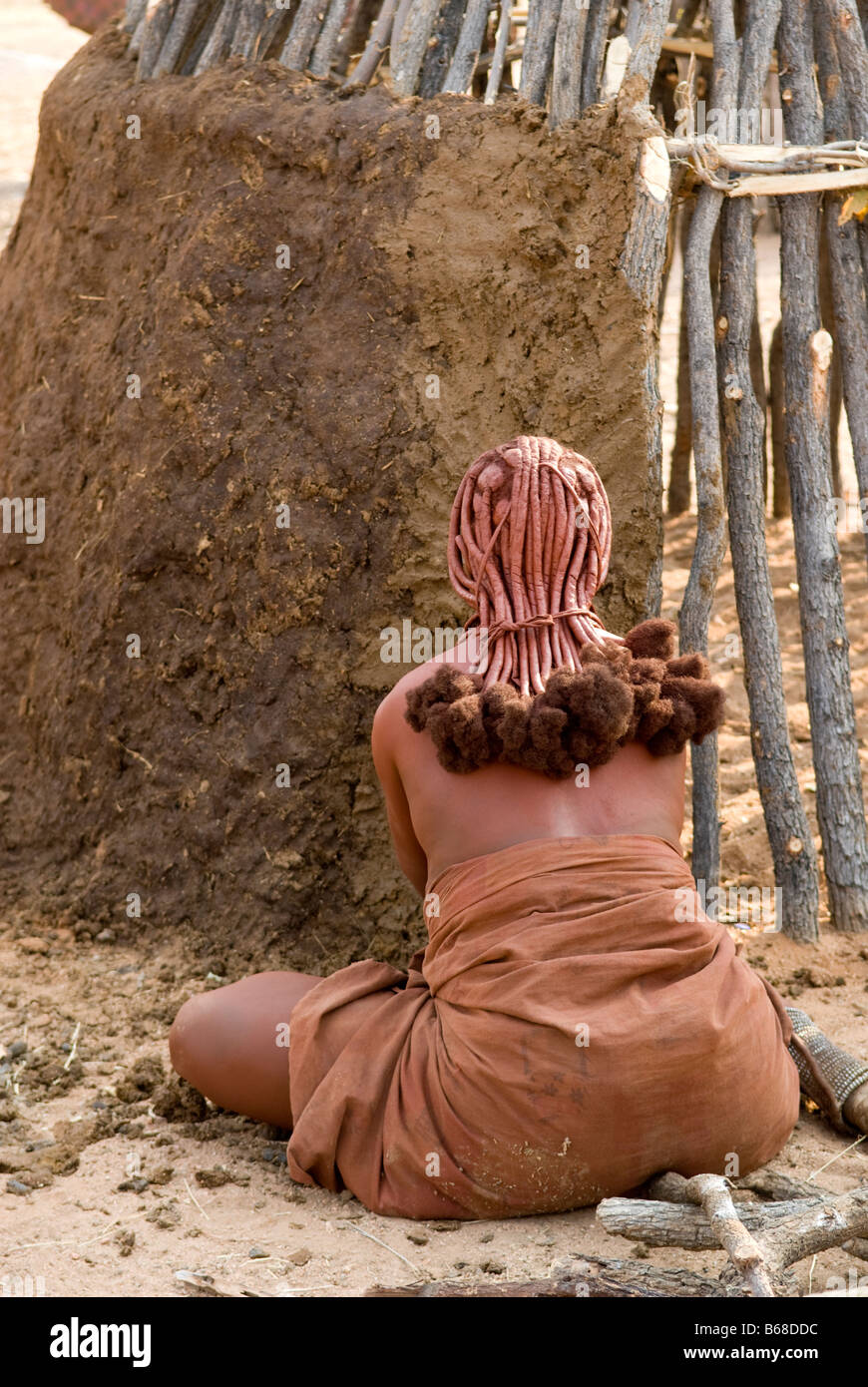 A young woman builds a traditionall village hut from sticks mud and ...