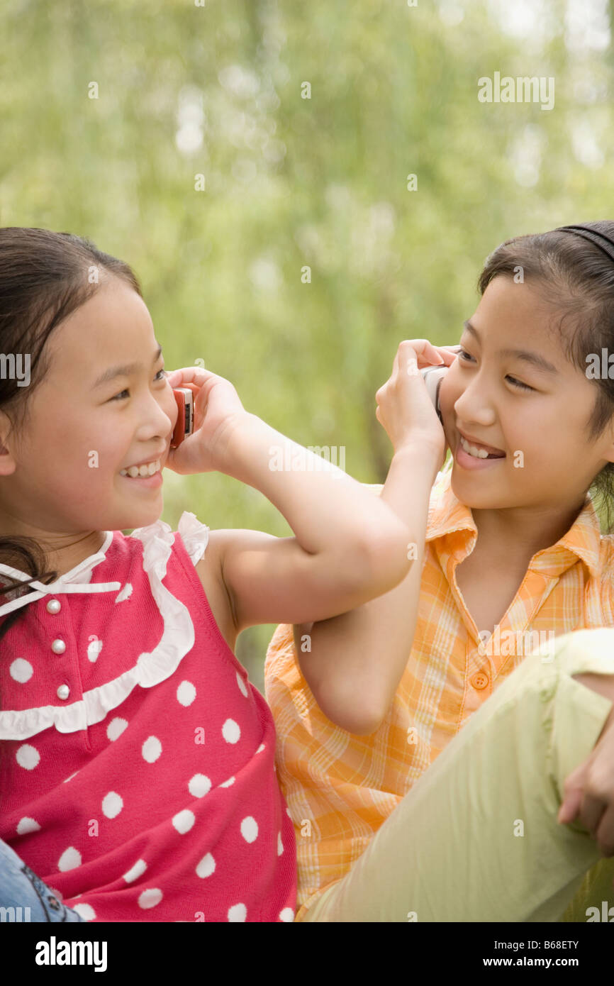 Two girls talking on their mobile phones and smiling Stock Photo - Alamy