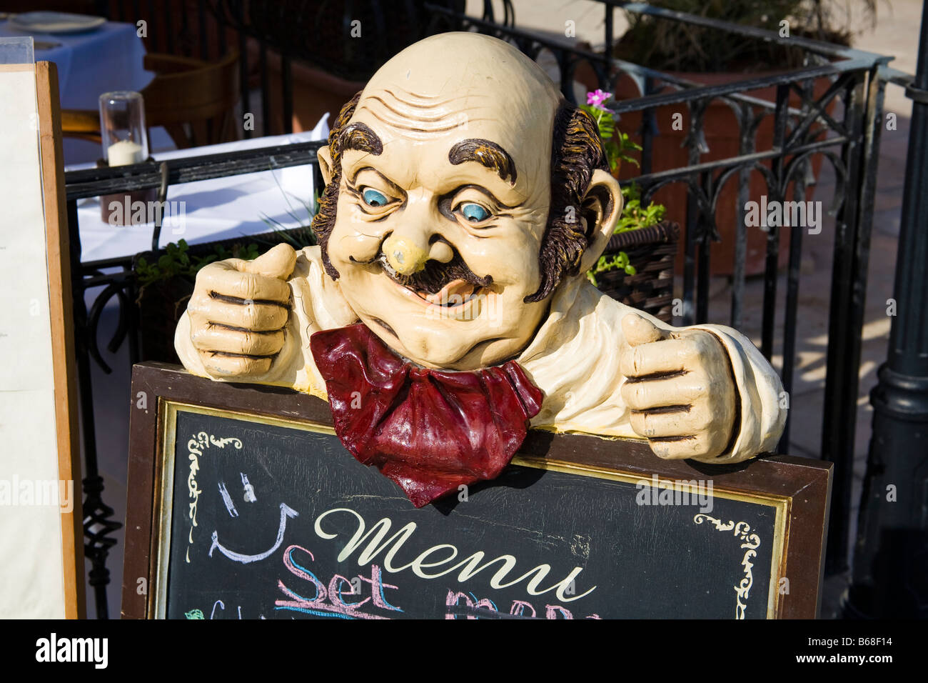 Carving of a man licking his lips above a menu board outside a ...