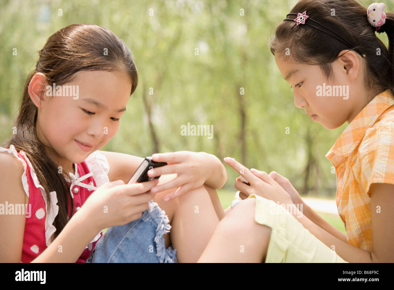 Two girls using their mobile phones Stock Photo - Alamy Two girls using their mobile phones Stock Photo - Alamy