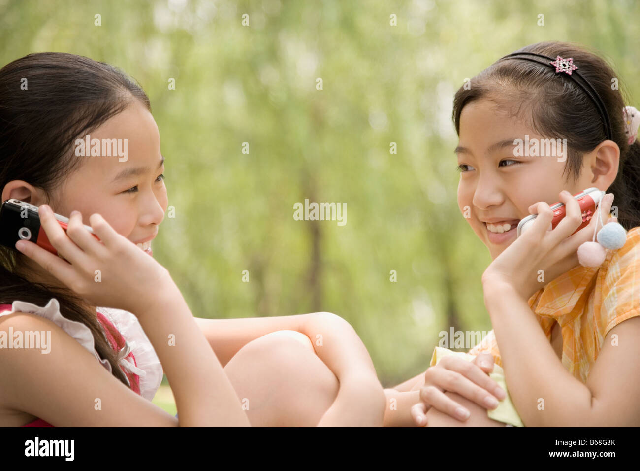 Two girls talking on their mobile phones and smiling Stock Photo - Alamy