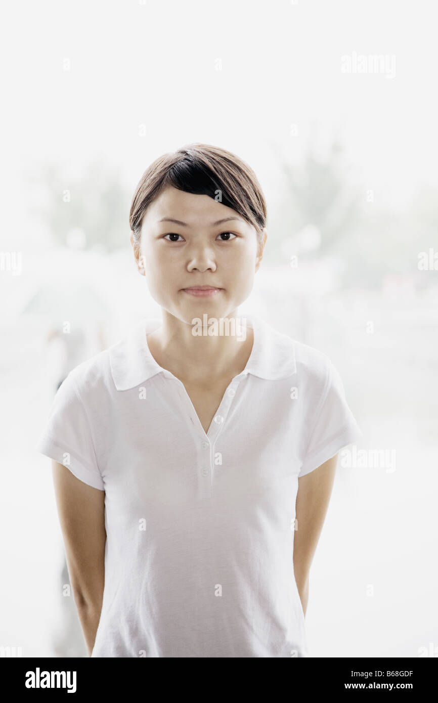 Portrait of a young woman standing with her hands behind her back Stock ...