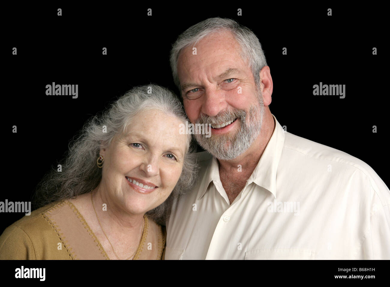 A good looking silver haired mature couple over a black background ...