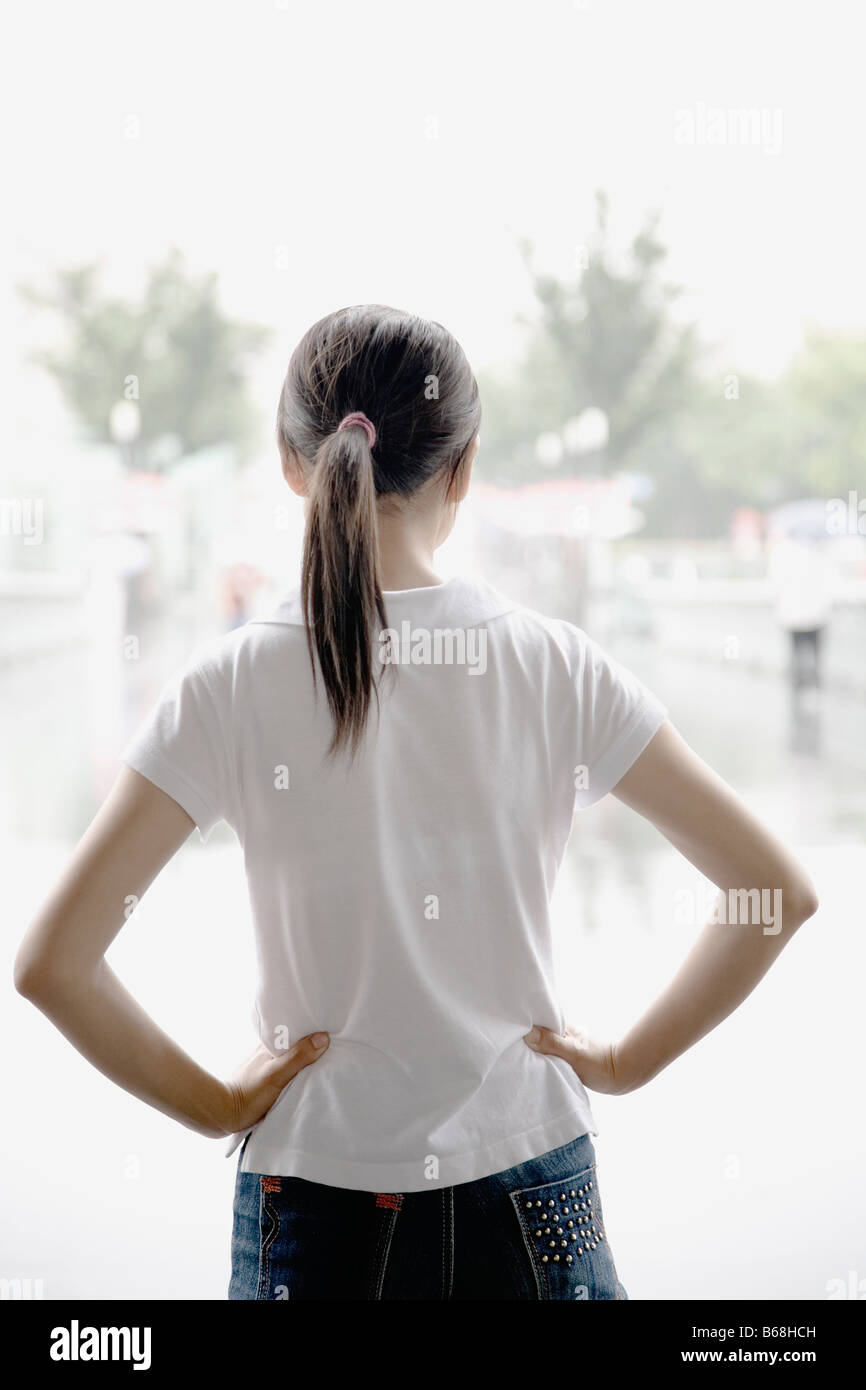 Rear view of a woman standing with her arms akimbo Stock Photo - Alamy