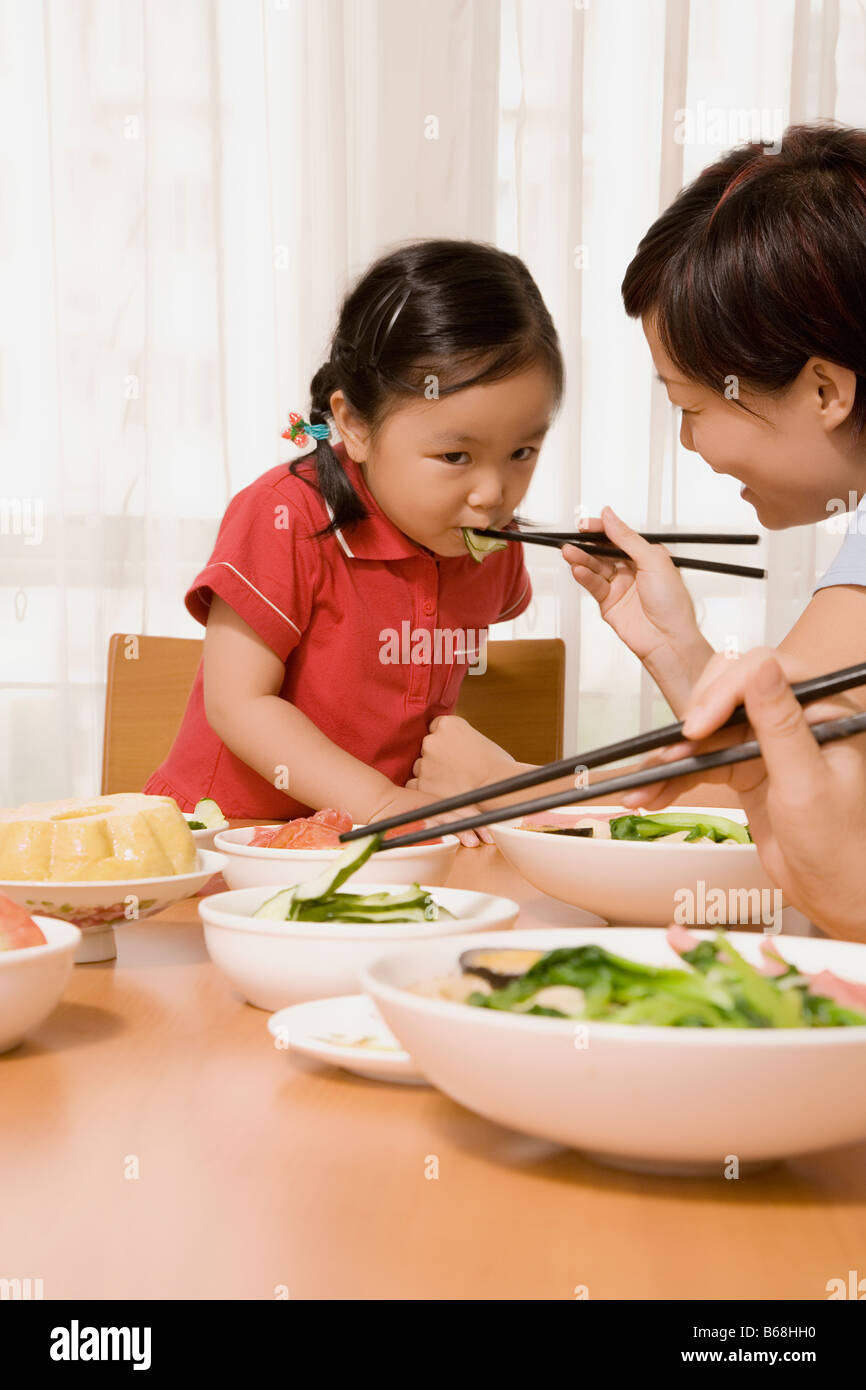 Side profile of a mid adult woman feeding her daughter Stock Photo - Alamy