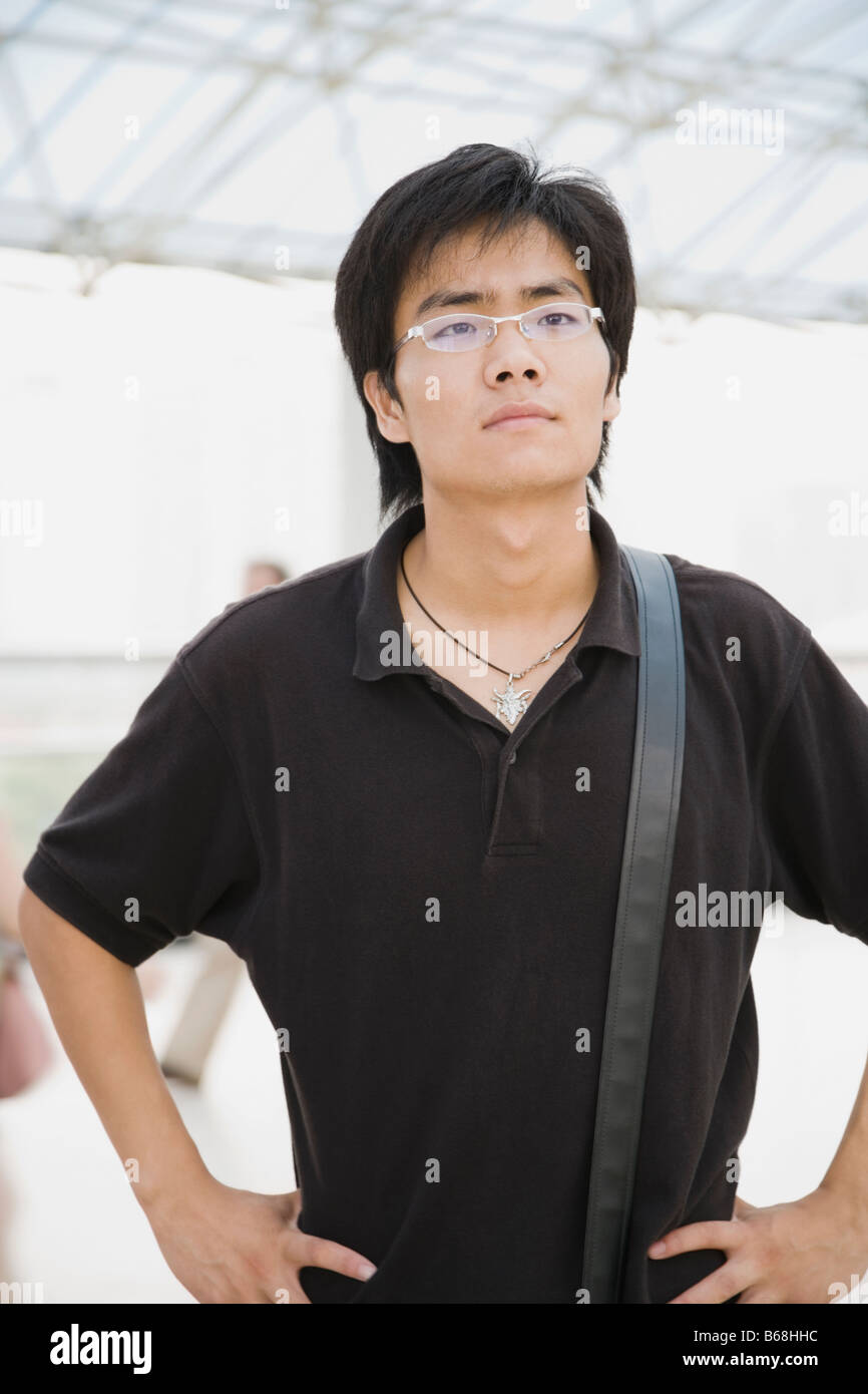 Young man standing with his arms akimbo Stock Photo - Alamy