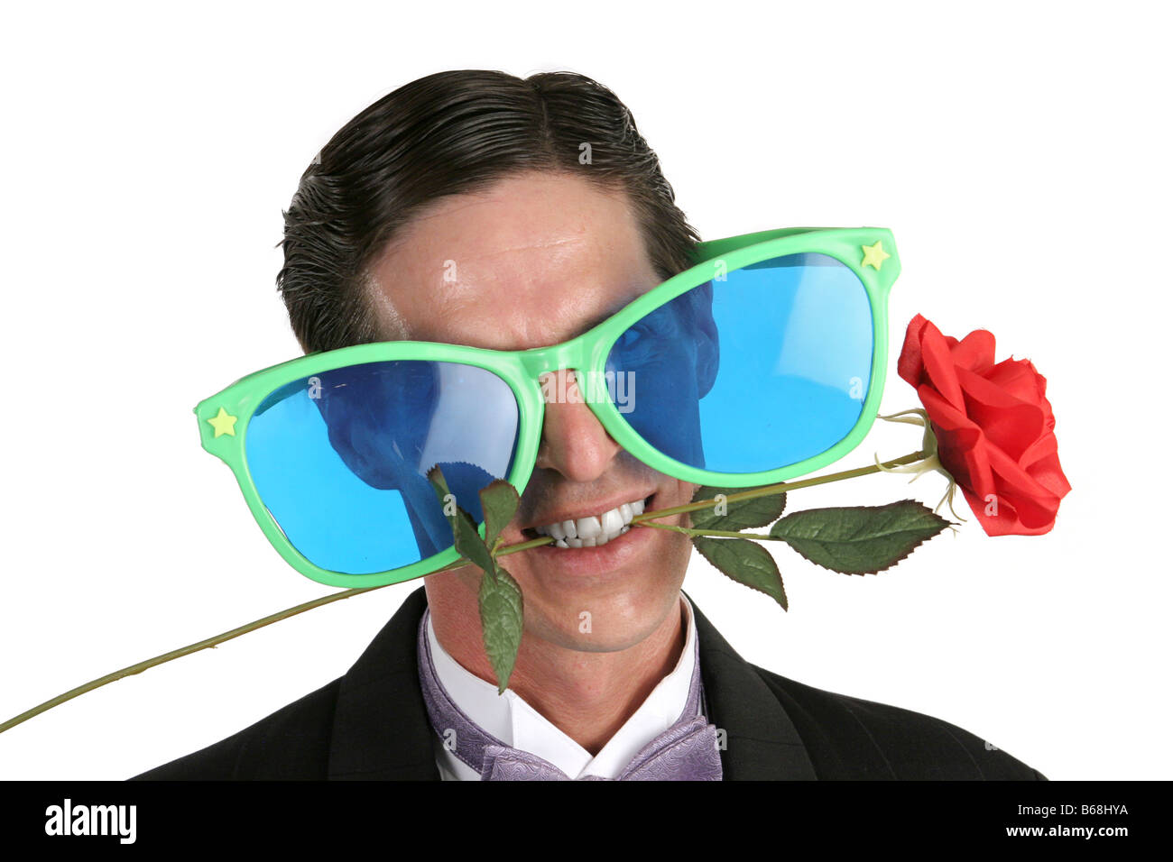 A handsome man in a tuxedo with a rose in his teeth and wearing ...