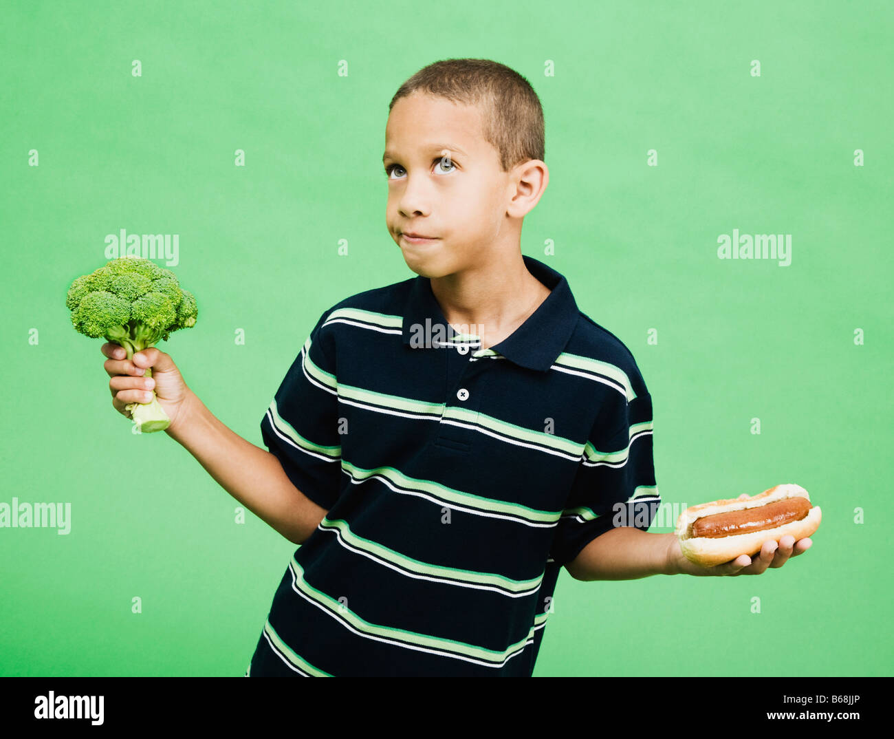 Boy (8-10) holding broccoli and hotdog, studio shot Stock Photo - Alamy