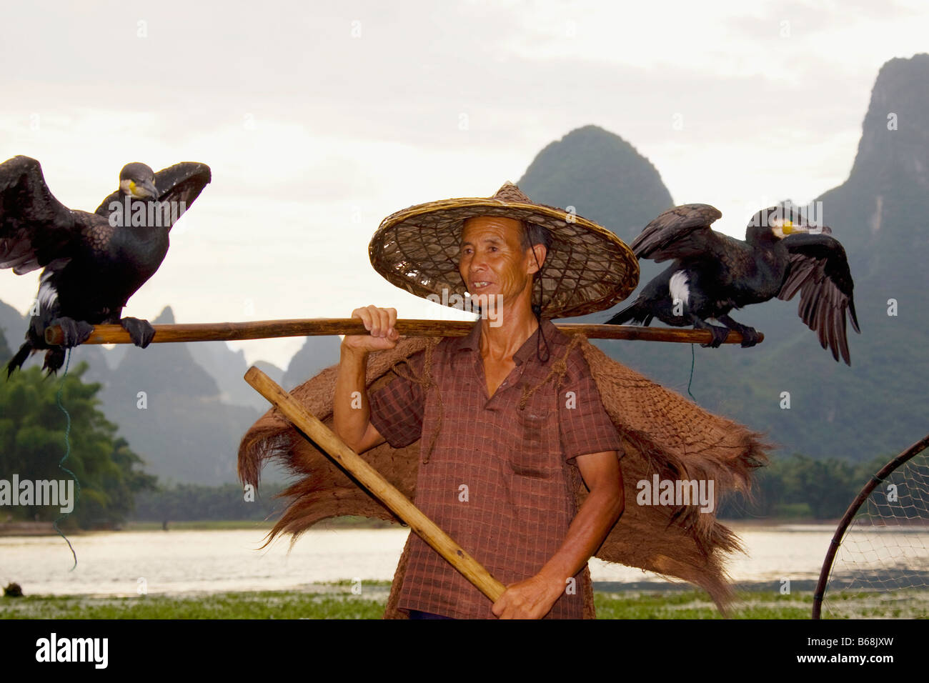 Senior man carrying two birds on his shoulders and smiling, Guilin ...