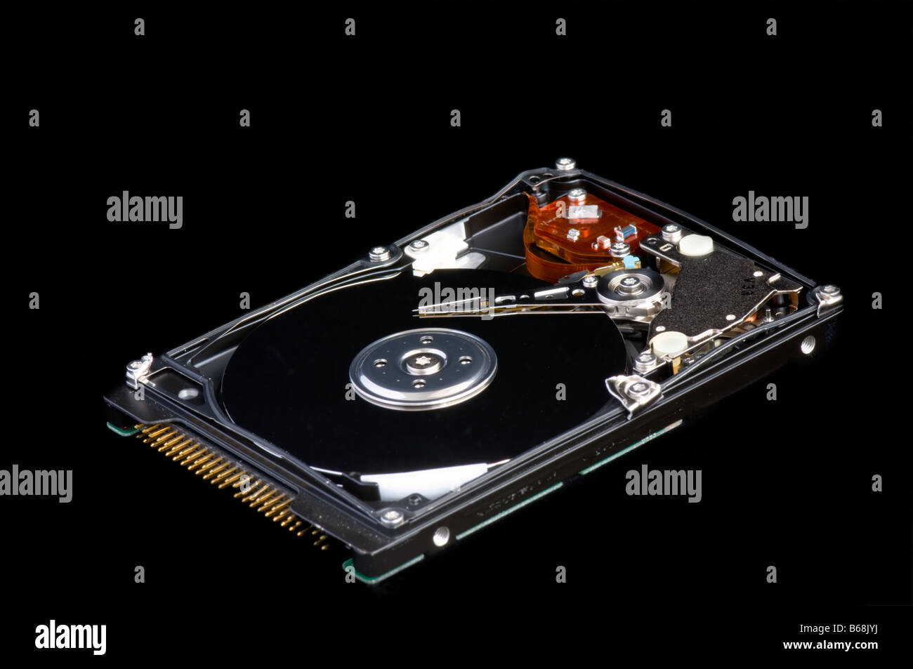 Opened hard disk showing the disk surface and drive head over black ...