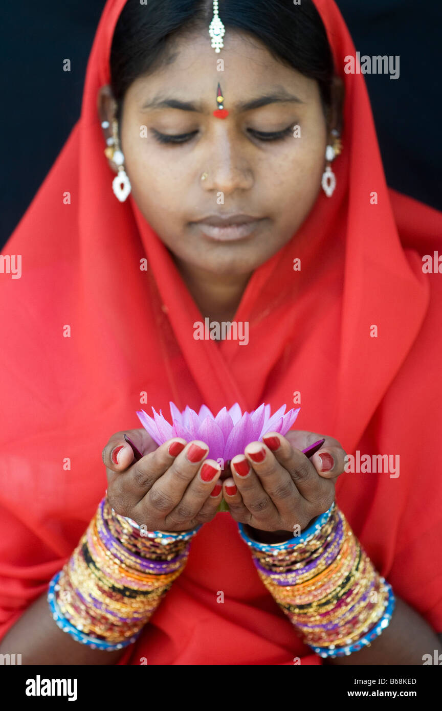 Indian woman offering a Nymphaea Tropical waterlily flower in a red ...